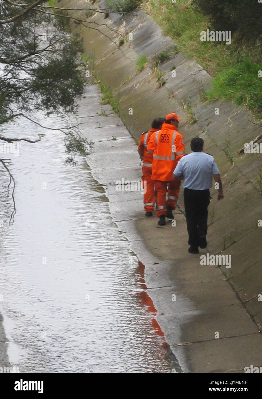SES crews conduct a line search along a creek that runs along a block ...