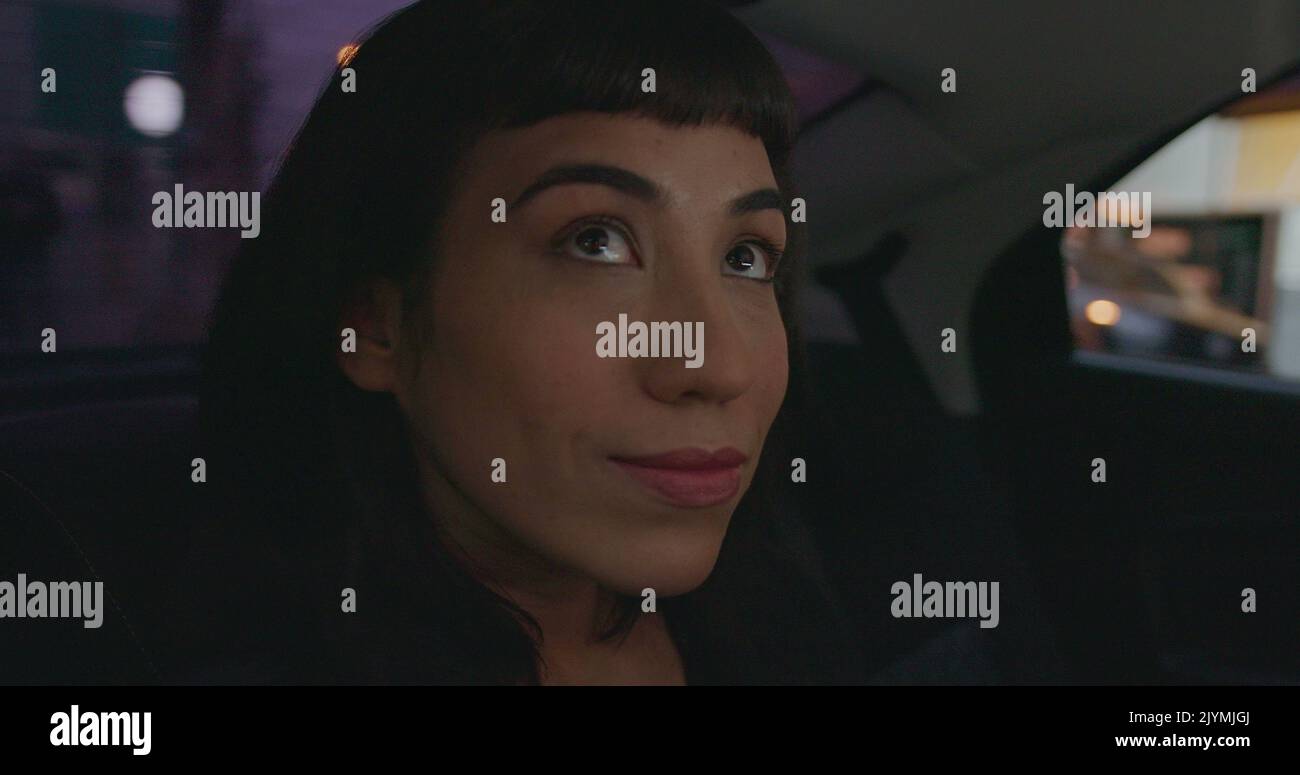 One happy hispanic woman in car backseat looking out vehicle window ...