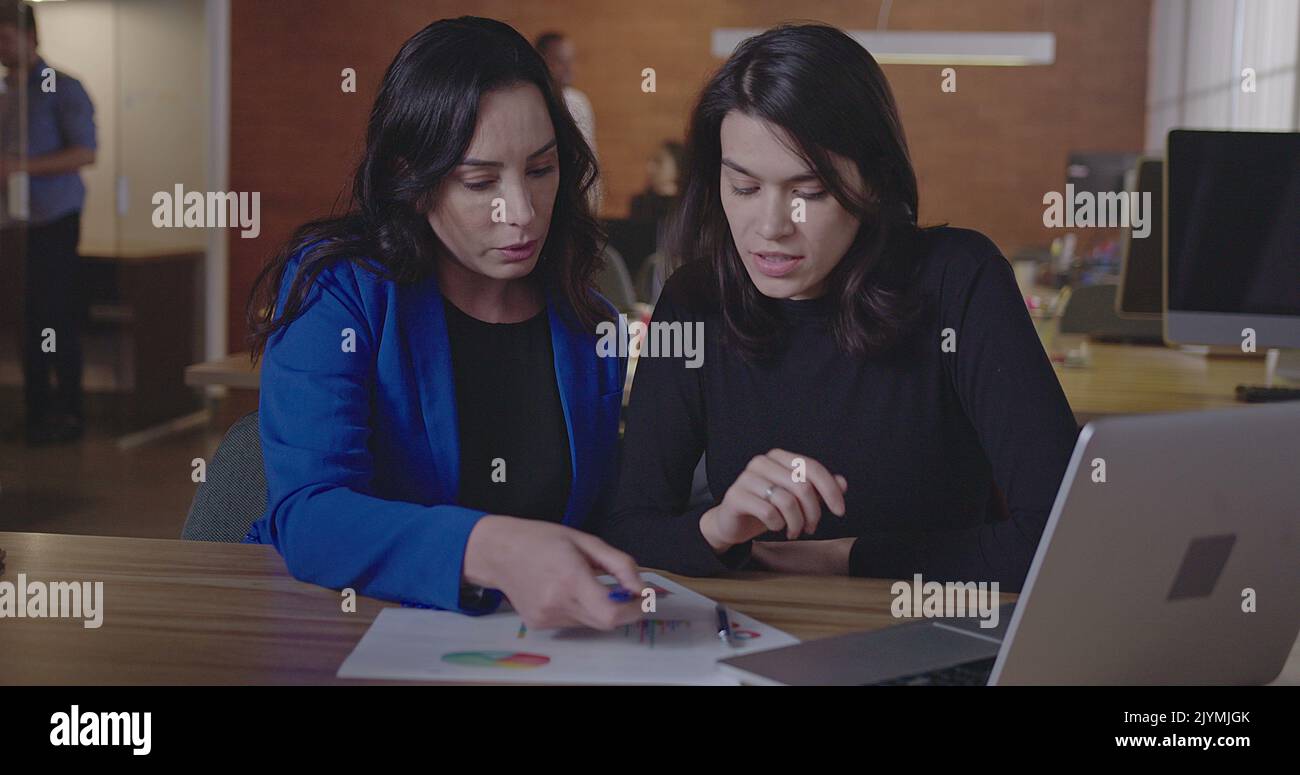 Two female employees working at night in the office. Modern workplace ...