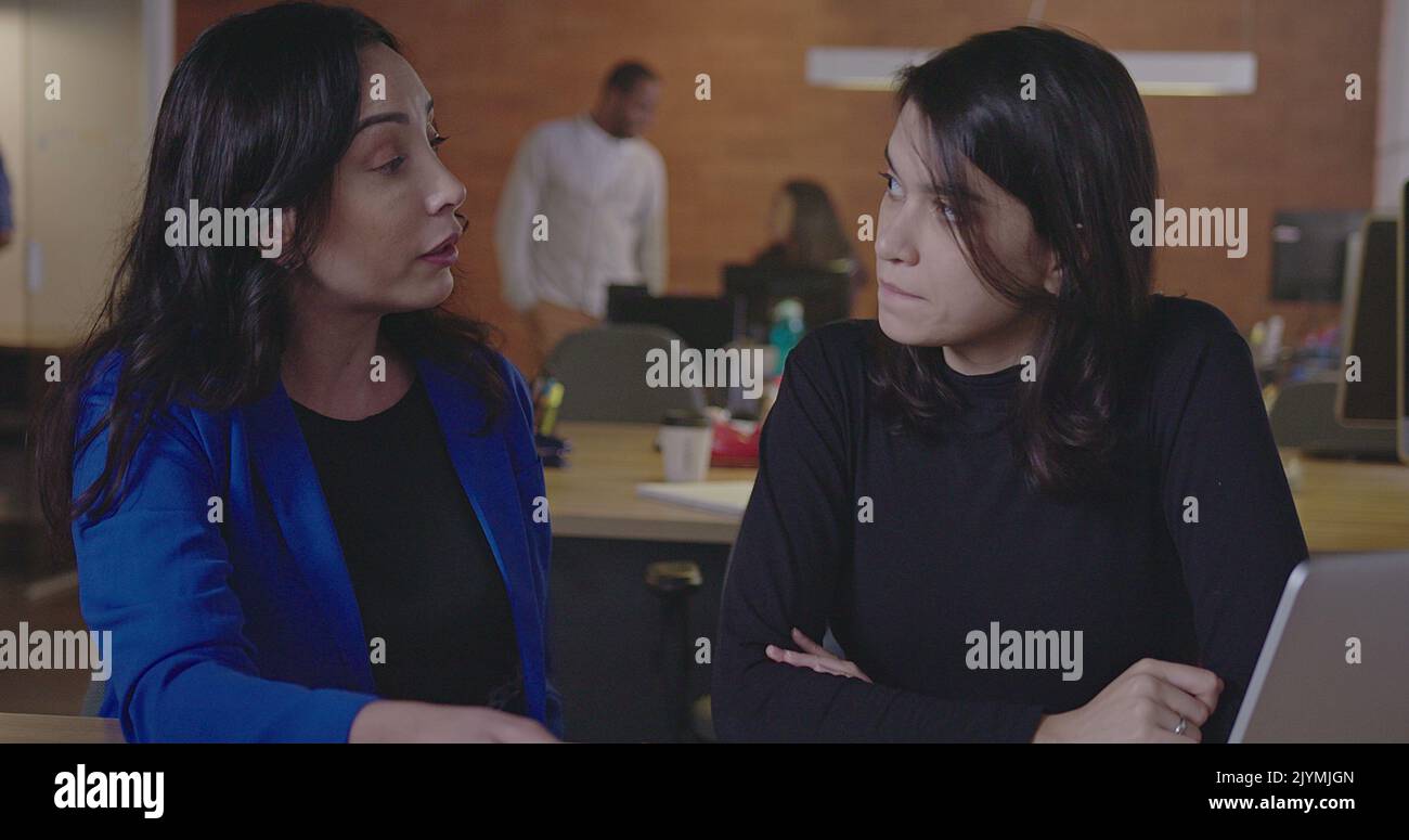 Two female employees working at night in the office. Modern workplace ...