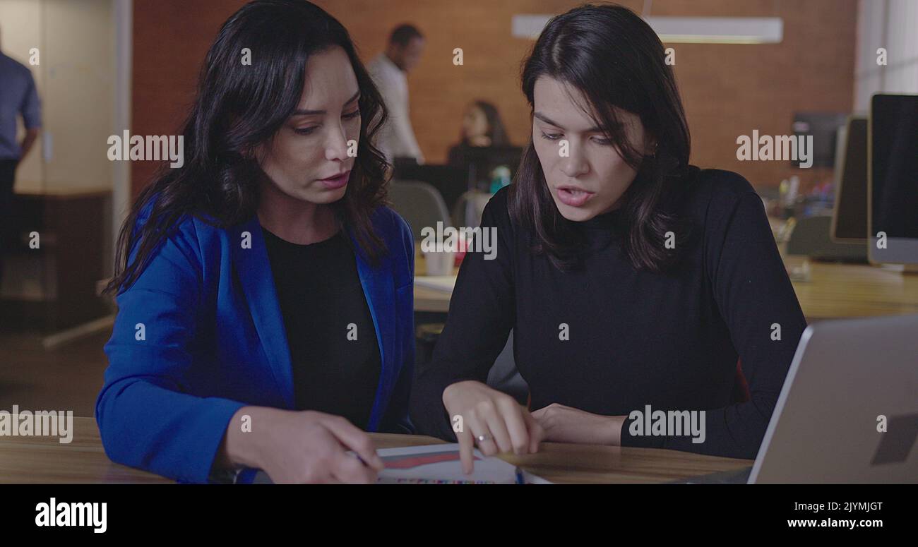 Two female employees working at night in the office. Modern workplace ...