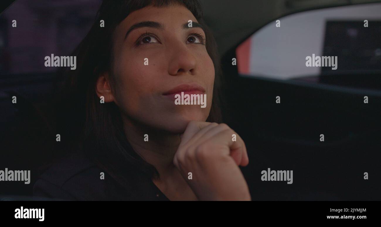Carefree woman looking at city through car window in car backseat ...