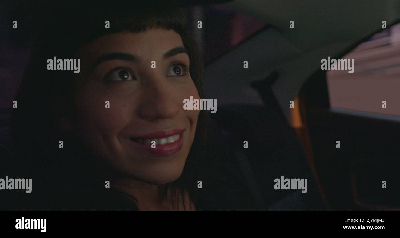 One happy hispanic woman in car backseat looking out vehicle window ...