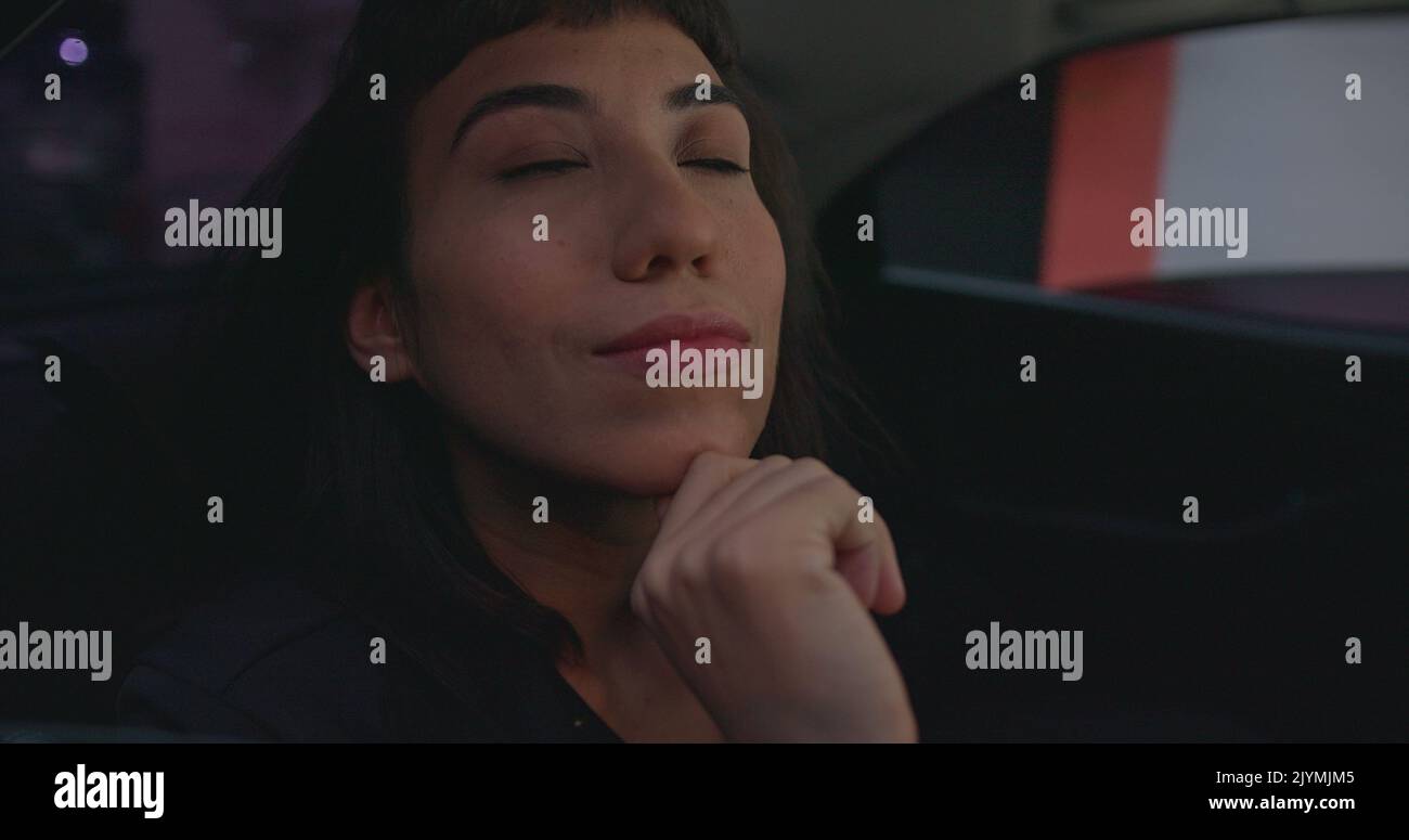 Carefree woman looking at city through car window in car backseat ...