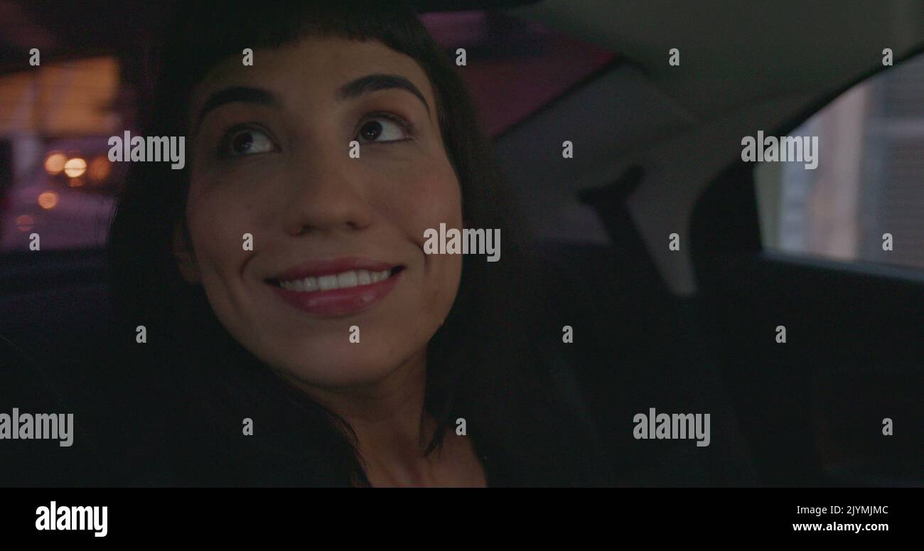 One happy hispanic woman in car backseat looking out vehicle window ...