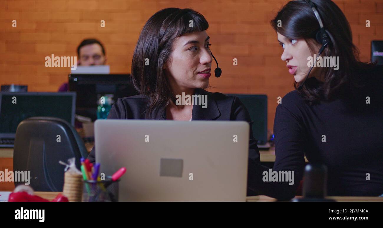 Female employee speaking with colleague at call center giving feedback ...