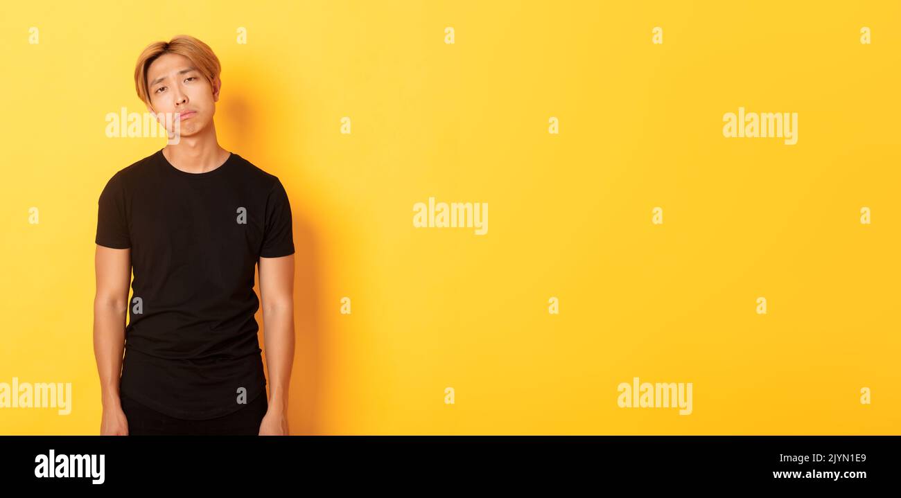 Portrait of exhausted and sad asian guy looking sad, standing drained ...