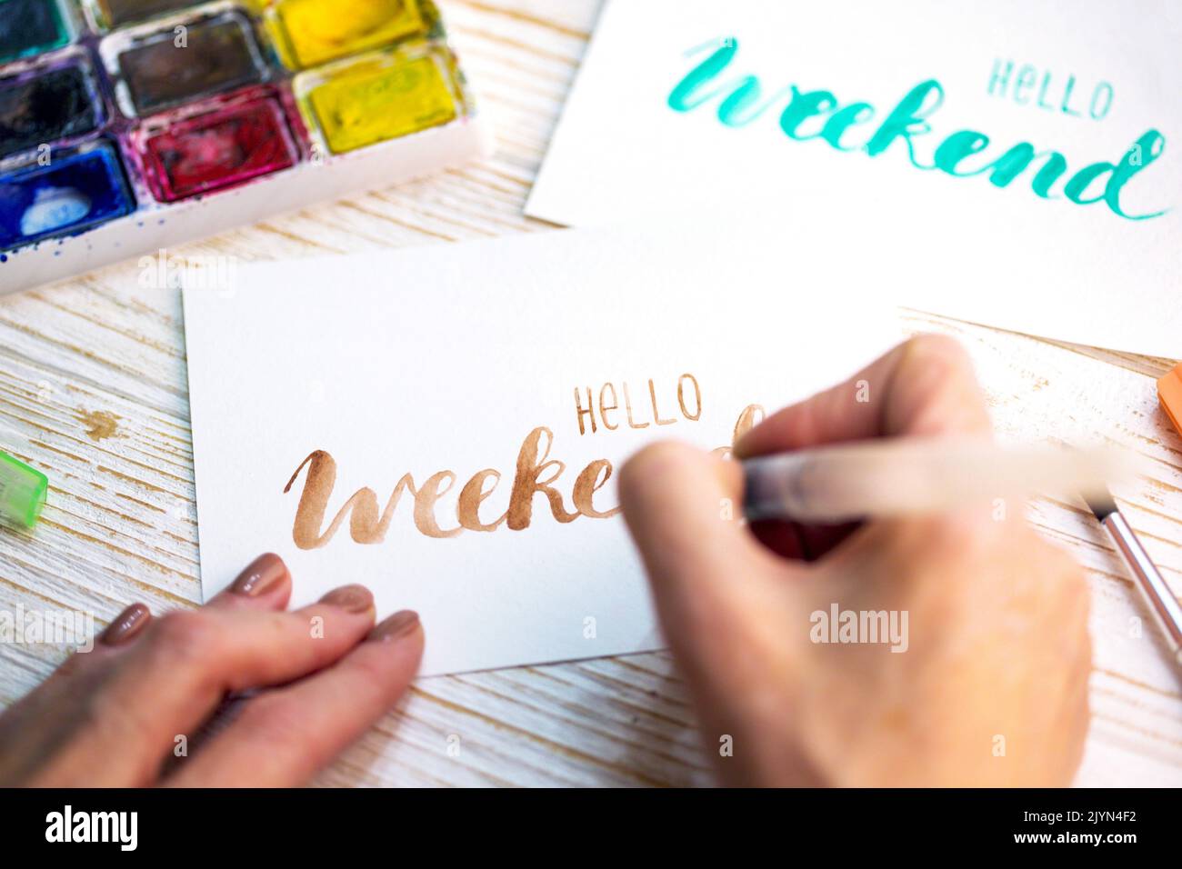 girl makes the inscription watercolor - hello weekend Stock Photo - Alamy