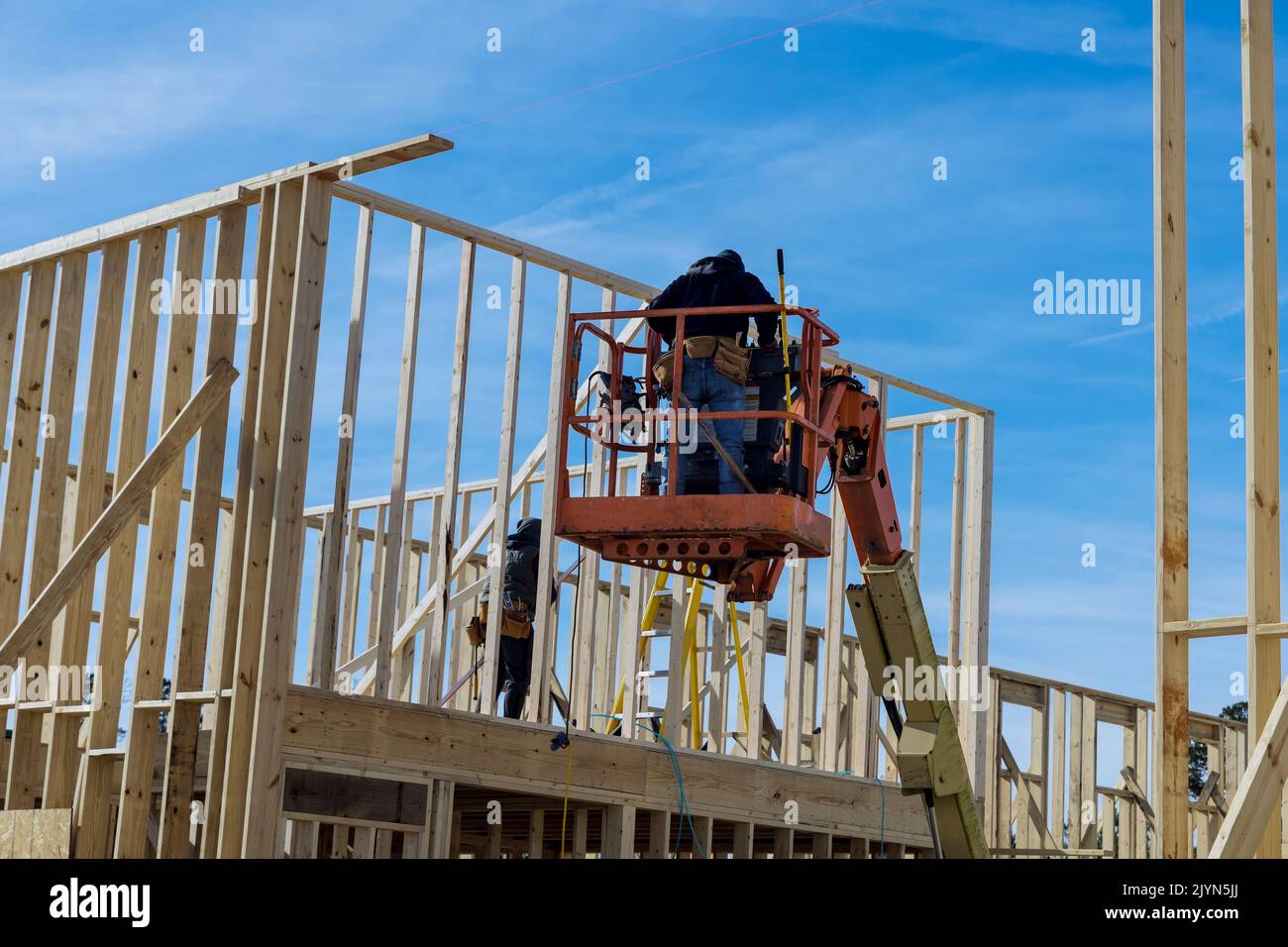 Working when the worker uses an air hammer to nail the beams of rafters ...