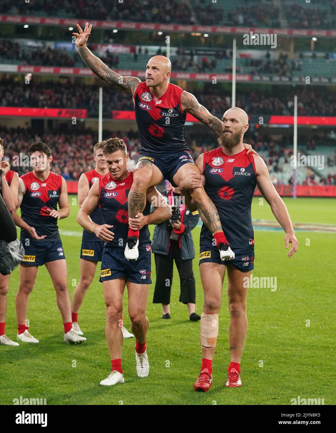 Nathan Jones of the Demons is chaired off the ground by Max Gawn of the ...