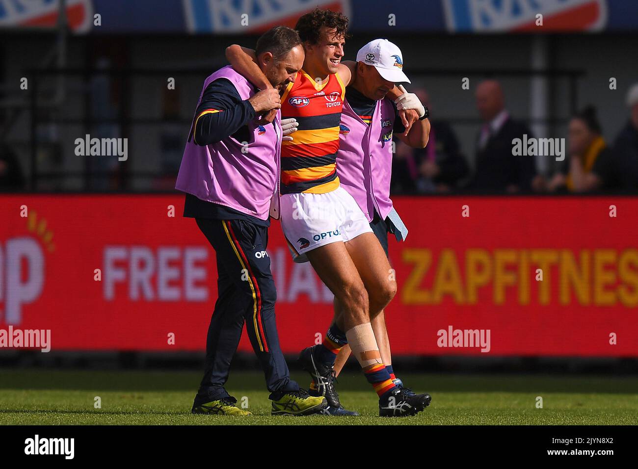 Will Hamill of the Adelaide Crows is assisted off the ground by medical ...