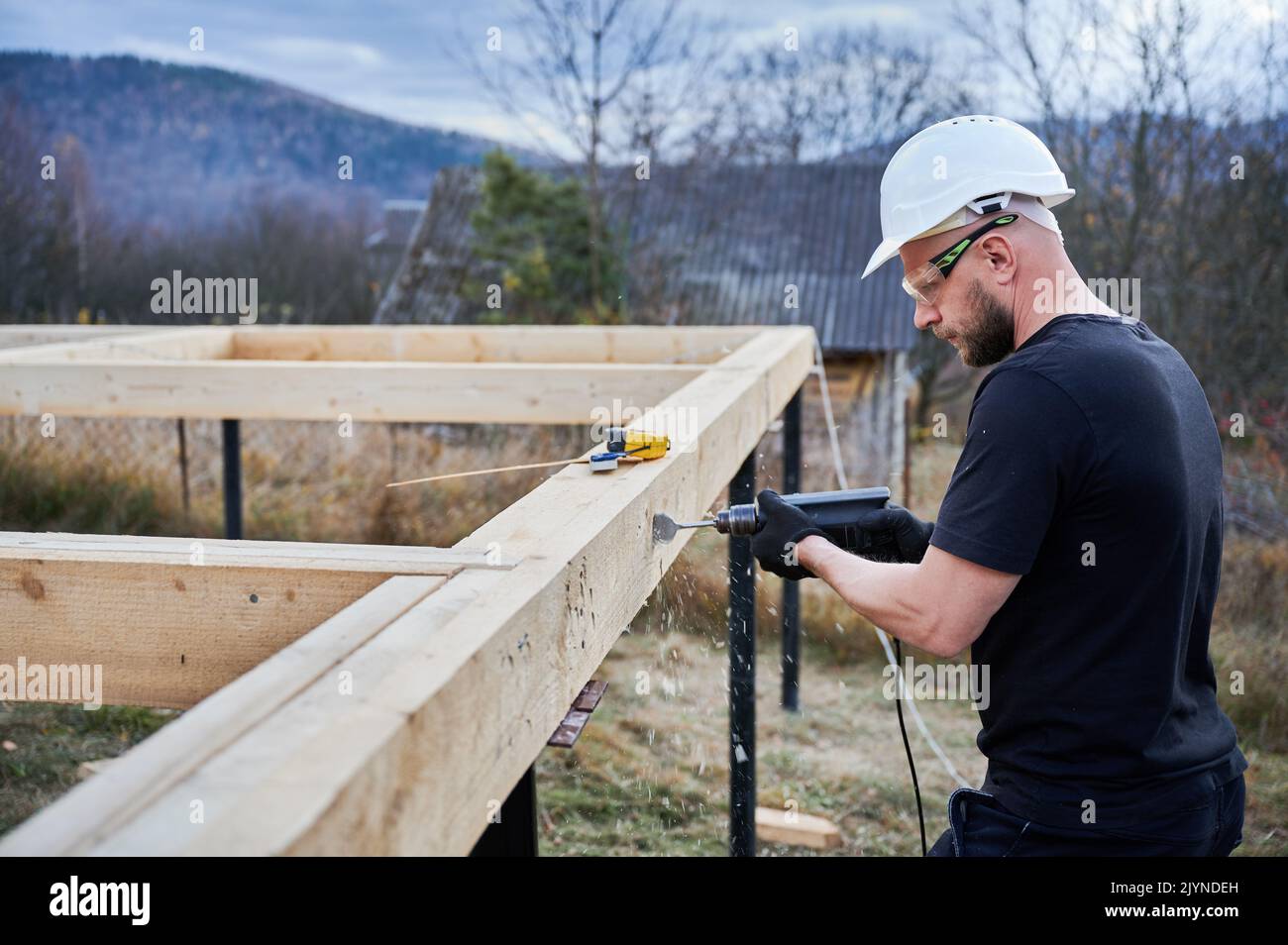 Man building wooden frame house on pile foundation. Male worker ...