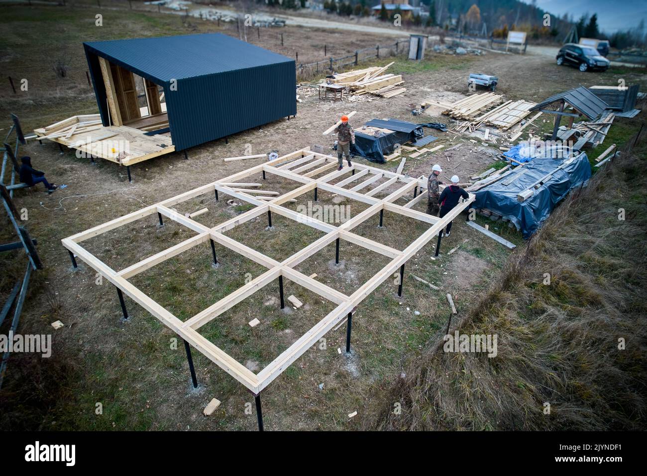 Men workers building wooden frame house on pile foundation. Carpenters ...