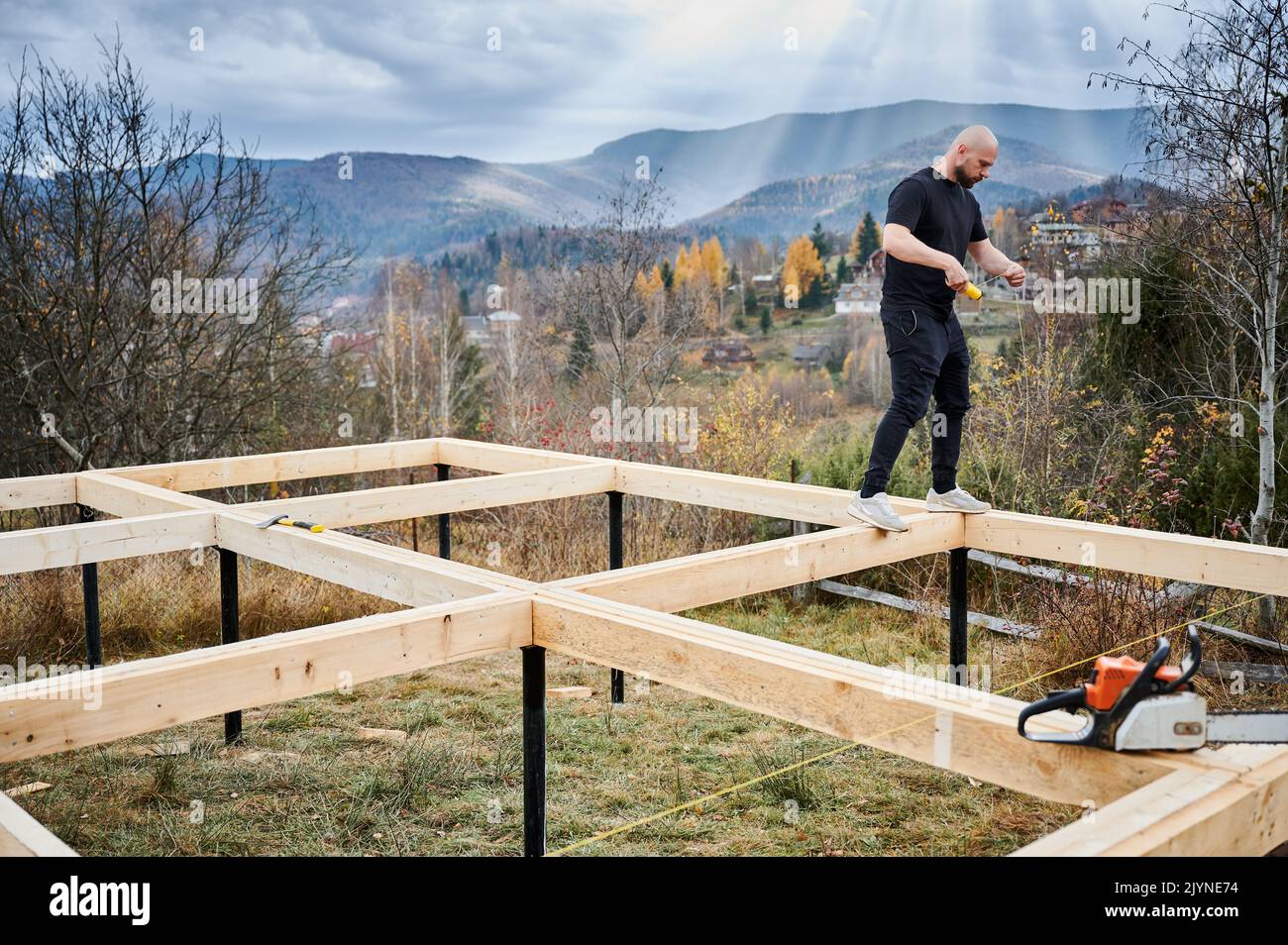 Man worker building wooden frame house on pile foundation in the ...