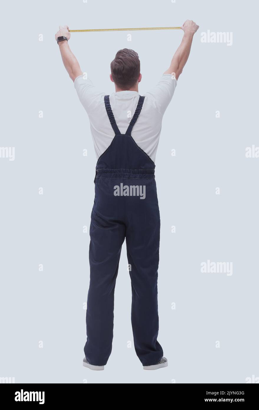 rear view. a man measuring something with a construction tape measure ...