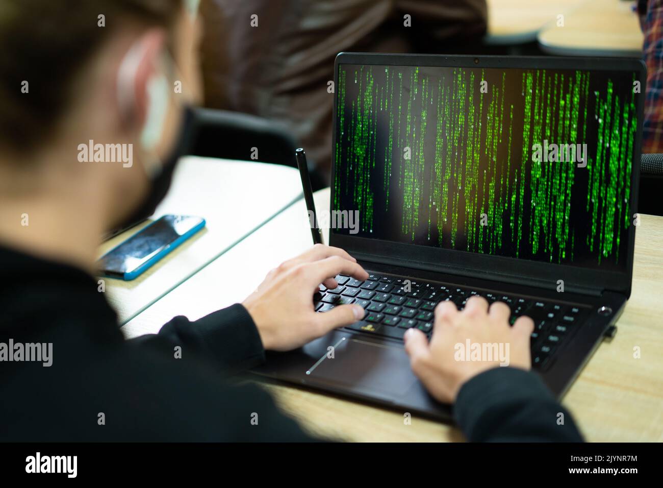 hacker writes code on laptop in matrix style Stock Photo - Alamy