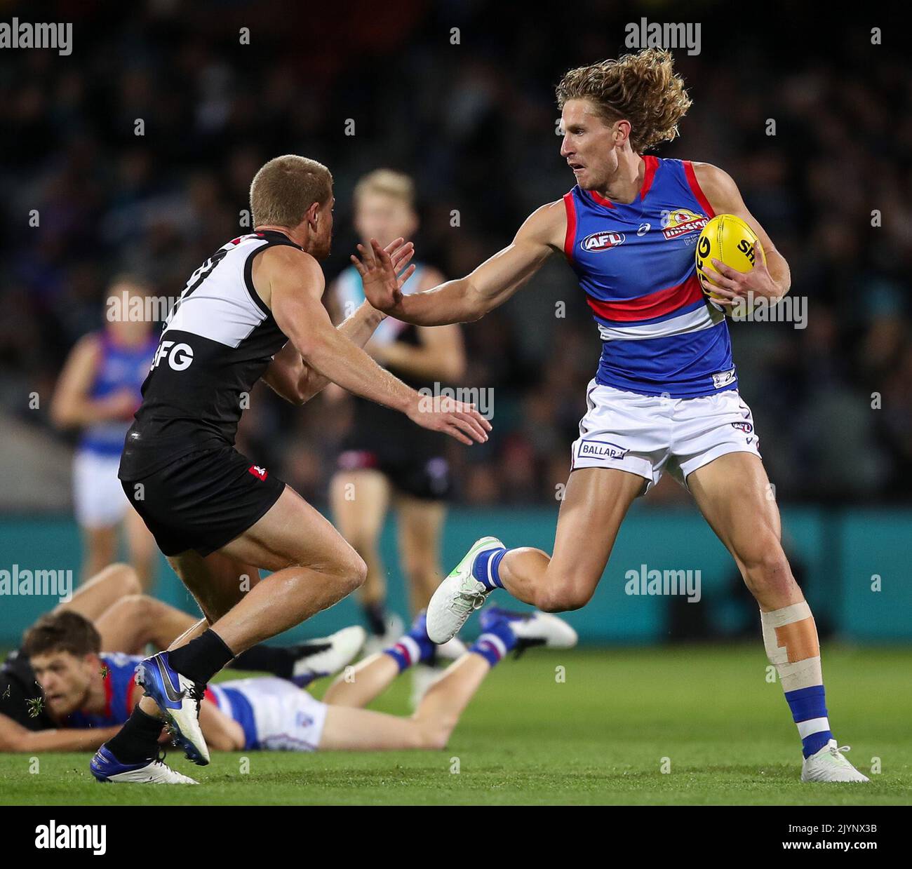 Aaron Naughton of the Bulldogs fends off Tom Clurey of the Power during ...
