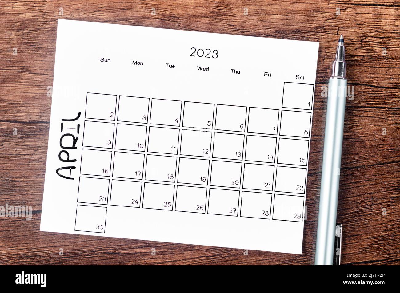 April 2023 Monthly calendar for 2023 year with pen on wooden table ...