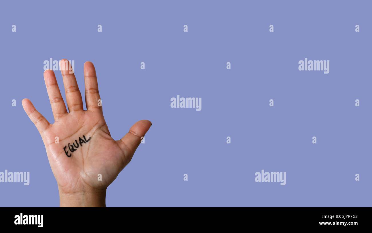 Word equal written on hand isolated on blue background. copy space ...
