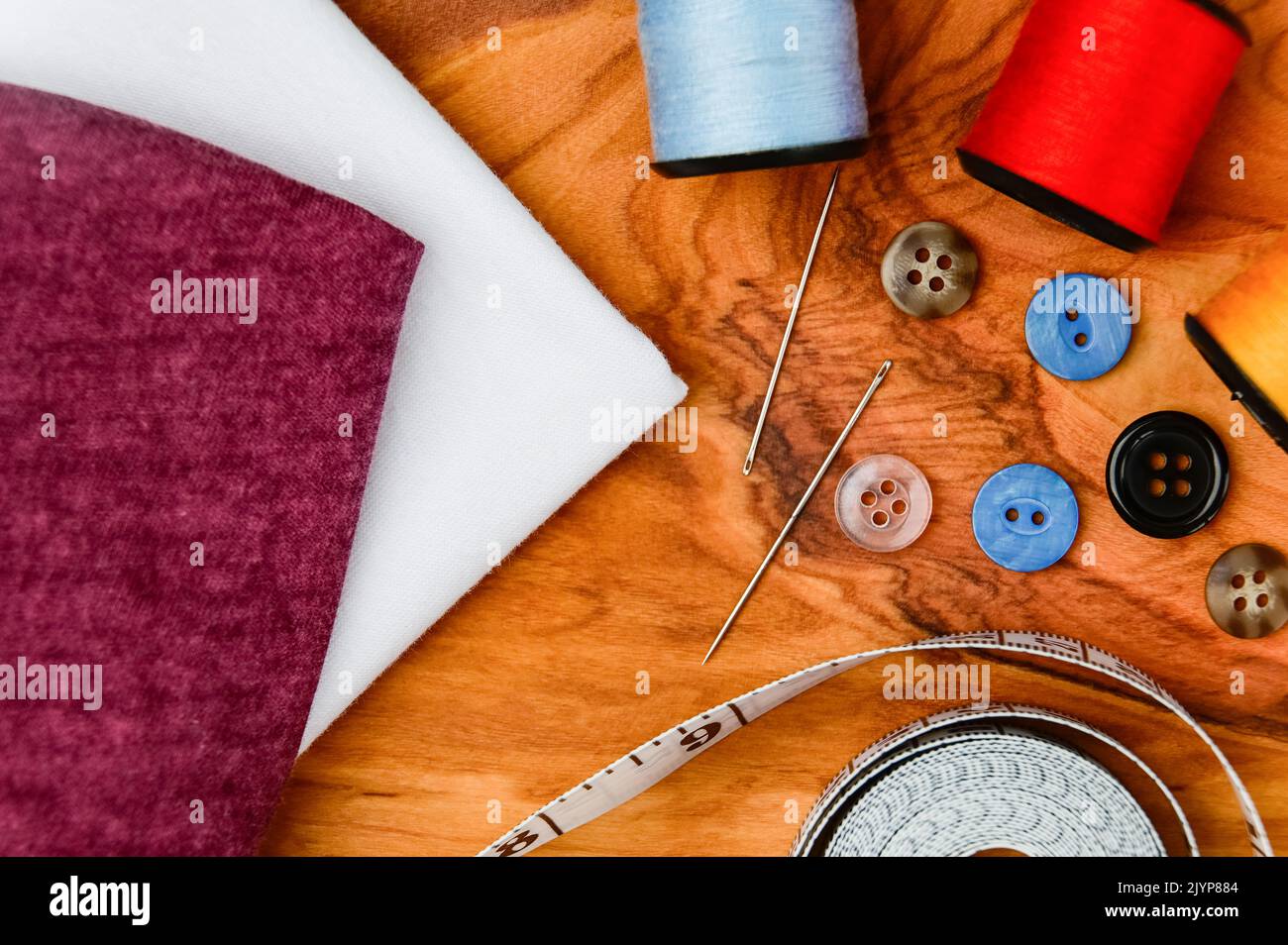 Sewing accessories and fabric on a wood background. Threads, needles ...