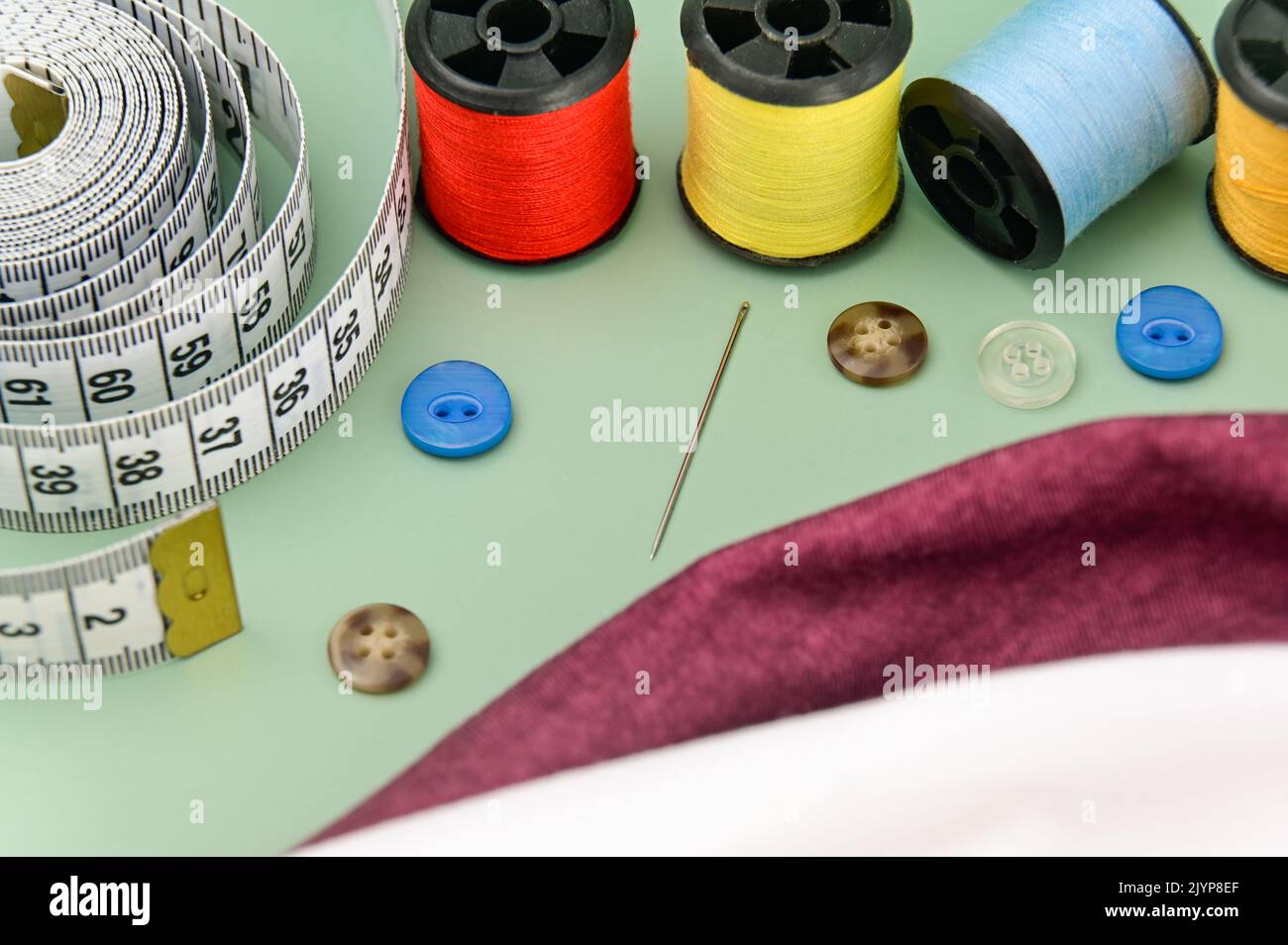 Sewing accessories and fabric on a green background. Including needle ...