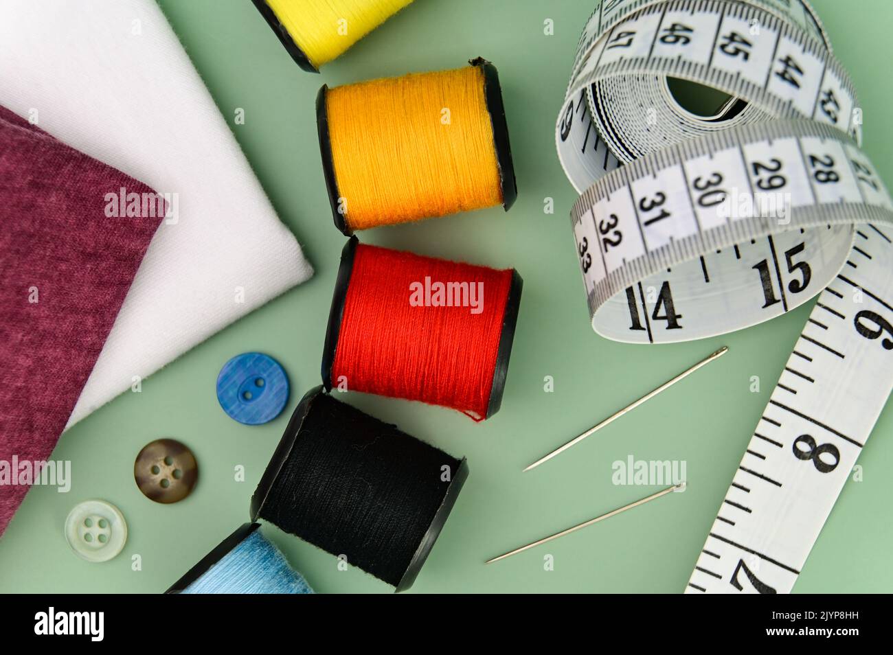 Sewing accessories and fabric on a green background. Including needle ...