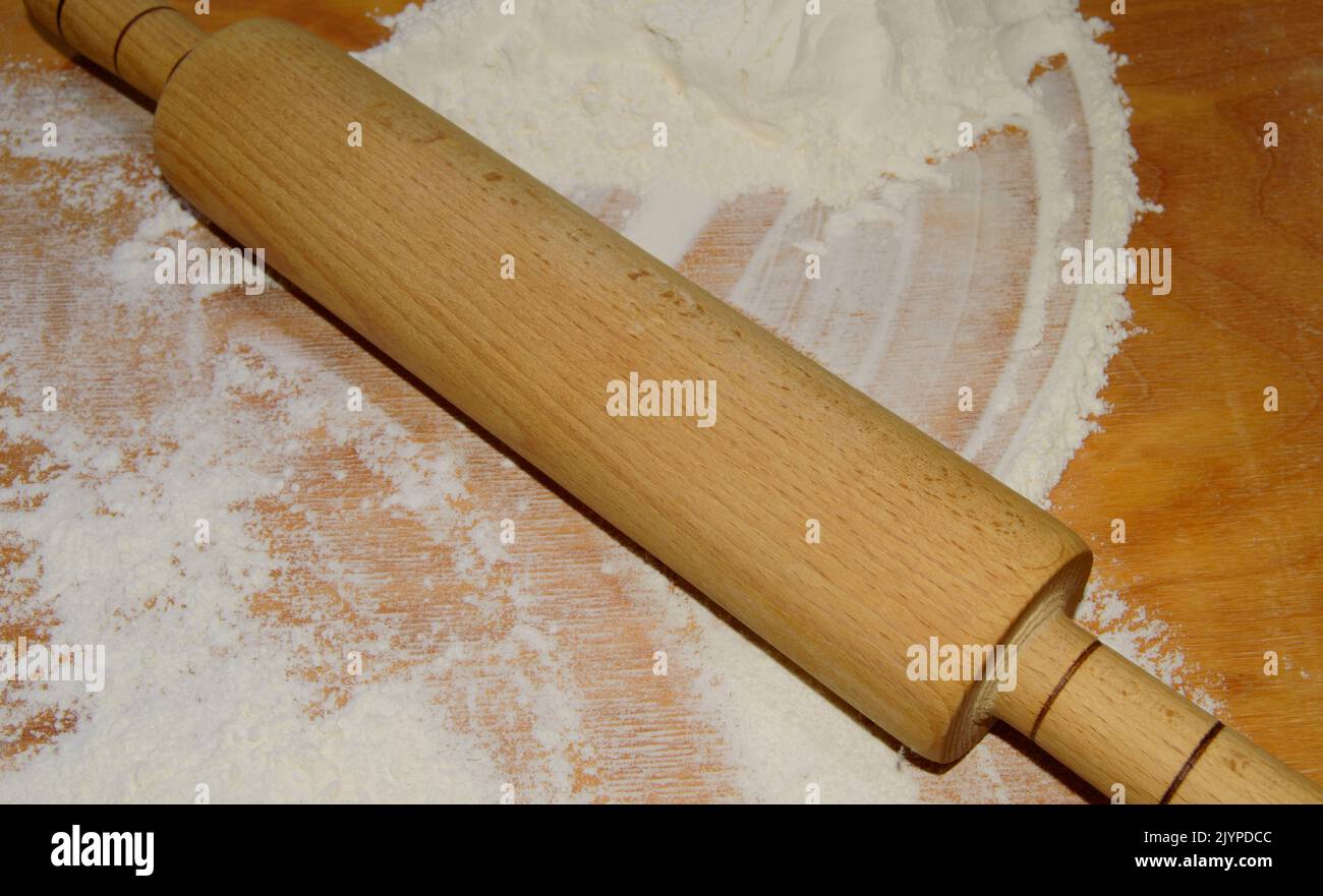 Rolling pin and kneaded dough are waiting on the wooden table for the ...
