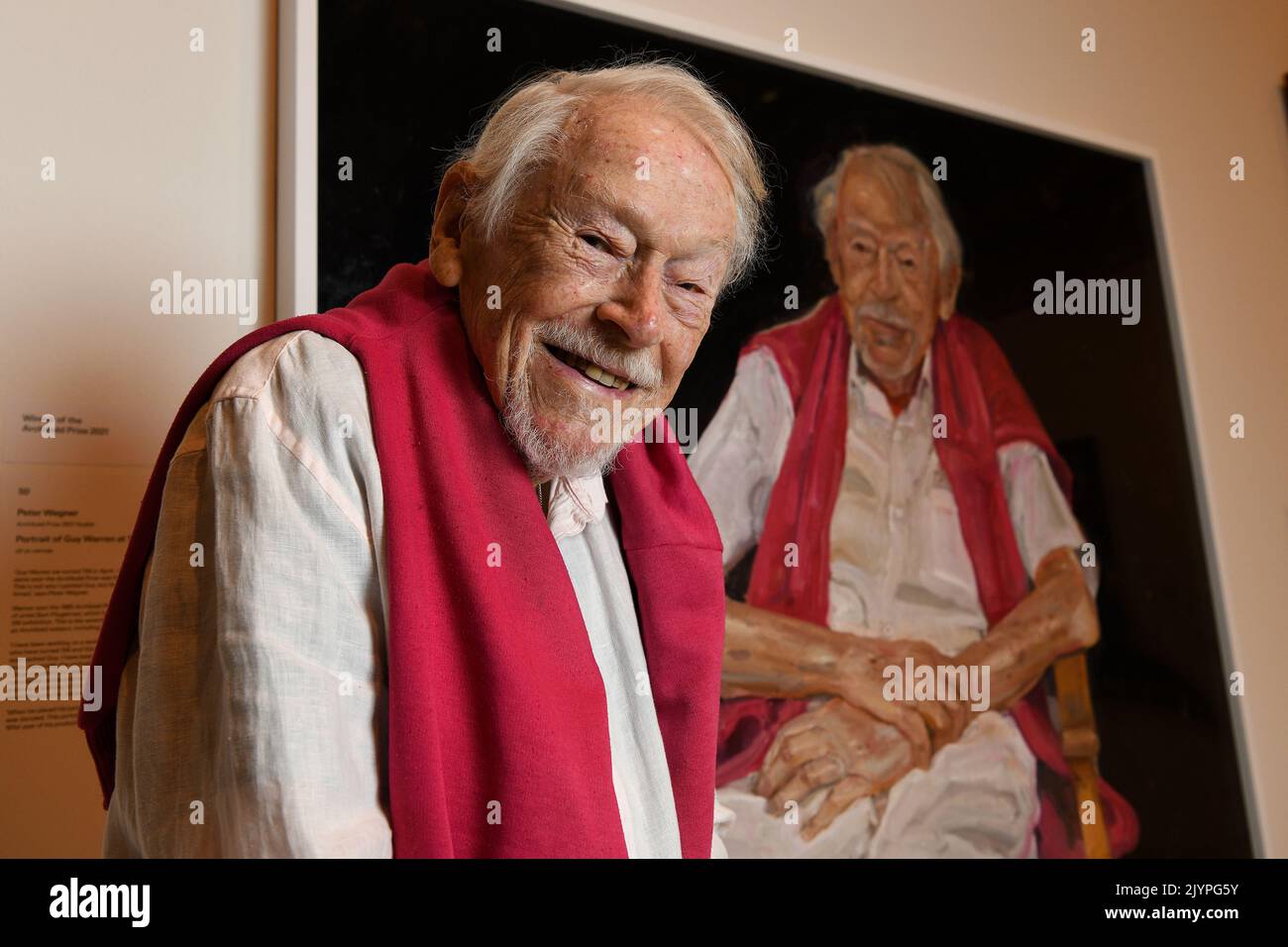 Guy Warren poses for a photograph in front of his portrait by artist ...