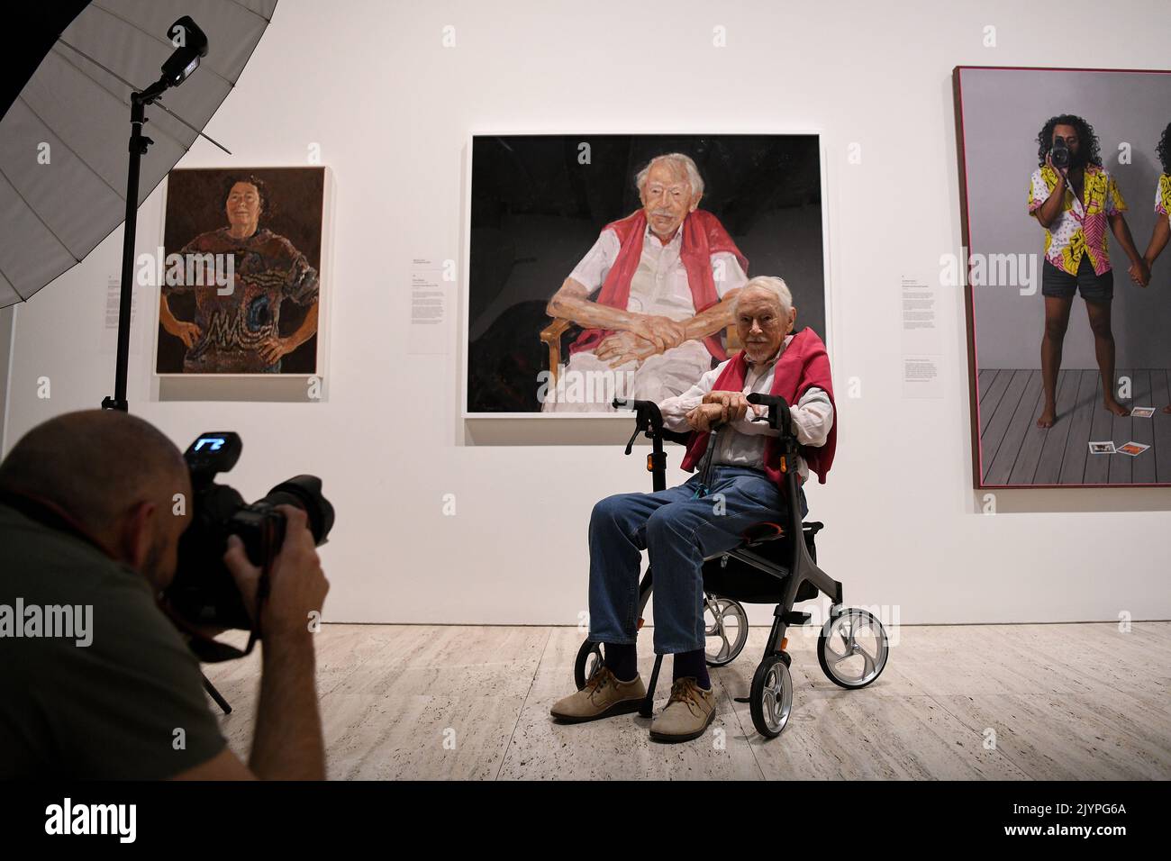 Guy Warren poses for a photograph in front of his portrait by artist ...