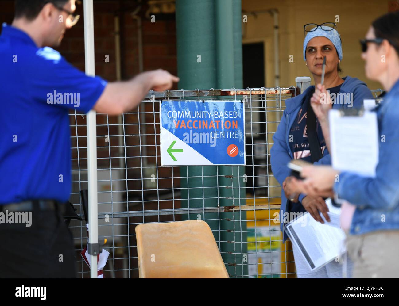 People are served by staff as they arrive to receive a coronavirus ...