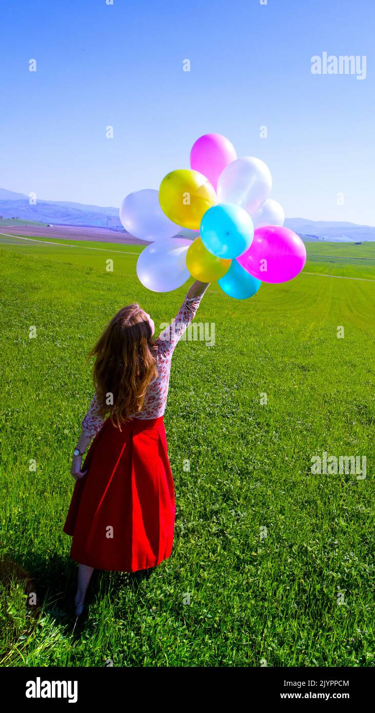 Happy girl in the meadows tuscan with colorful balloons, against the ...