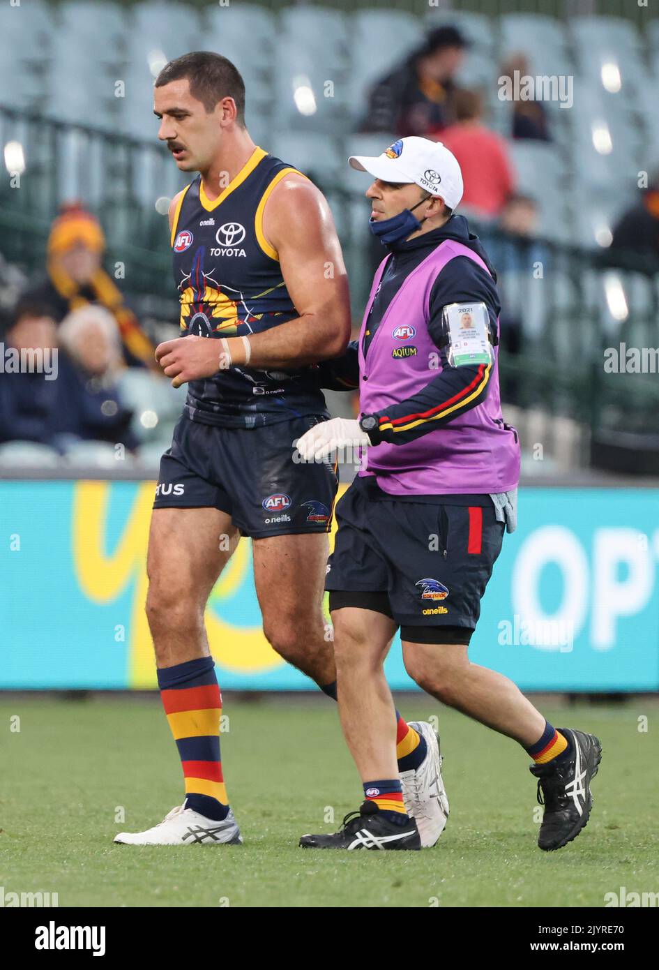 Taylor Walker of the Crows is helped off the field by a trainer during ...