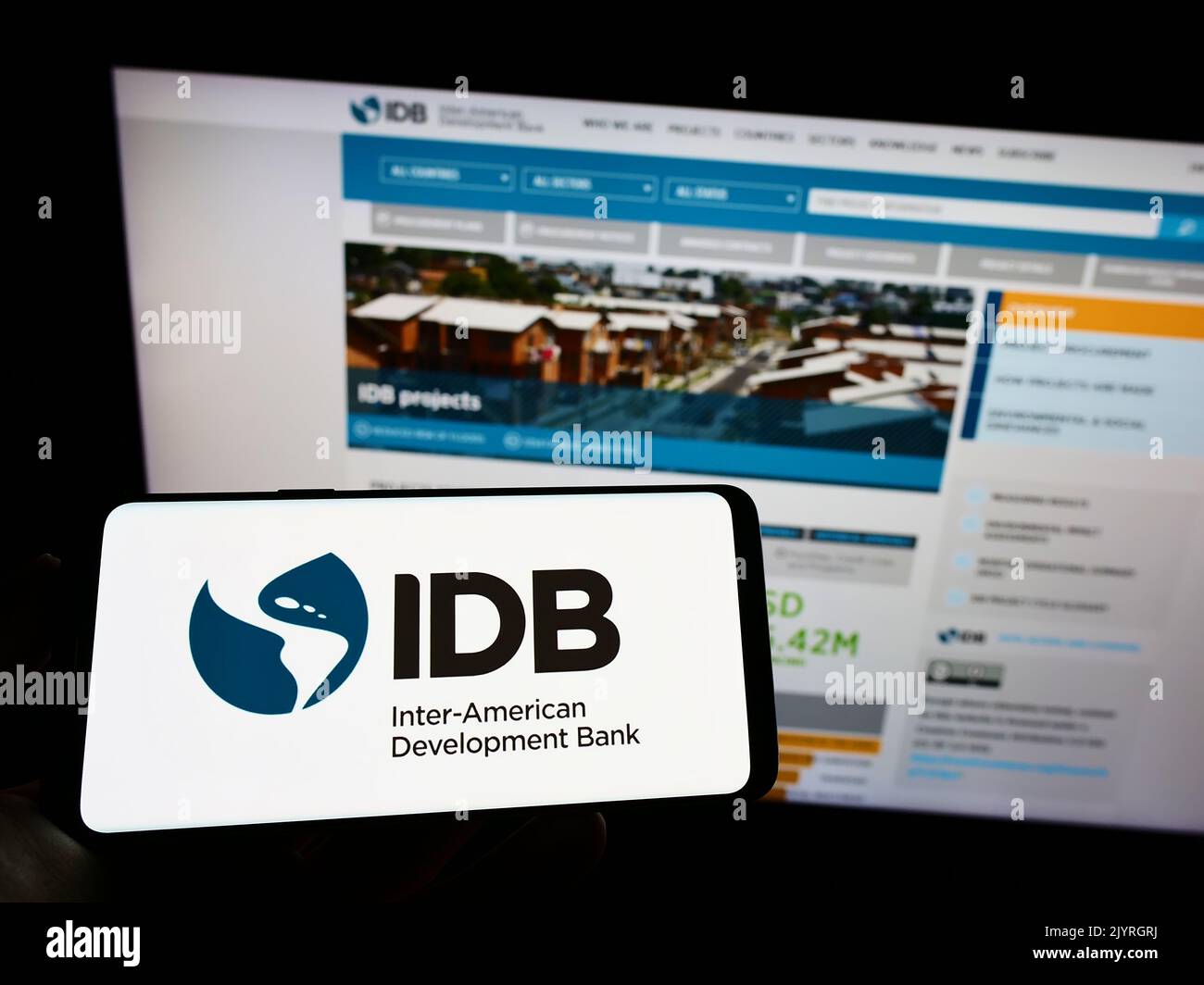 Person holding cellphone with logo of Inter-American Development Bank ...