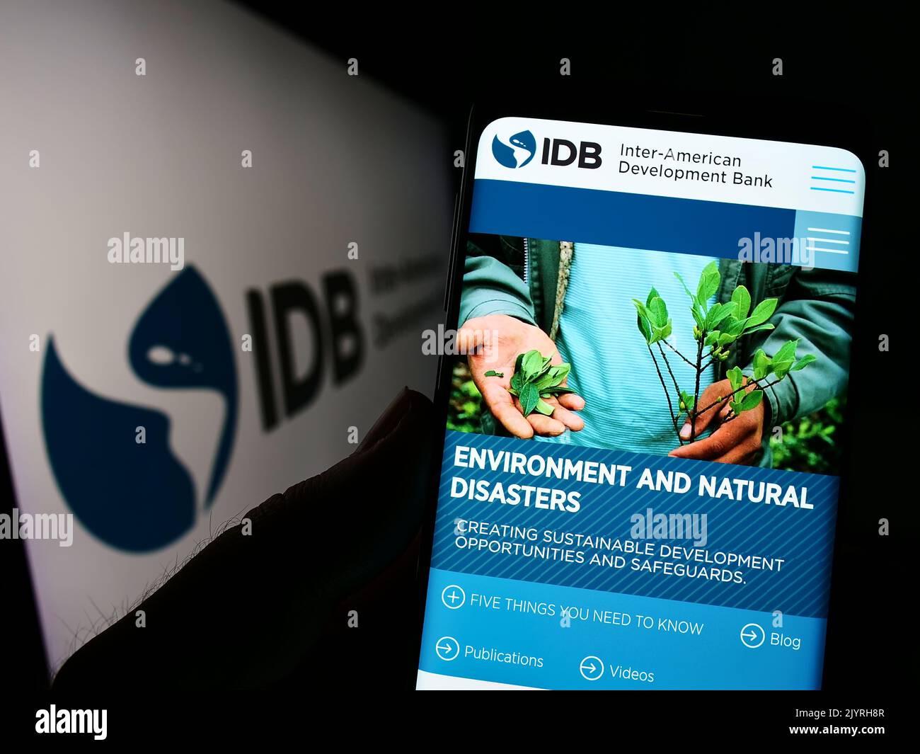 Person holding smartphone with website of Inter-American Development ...