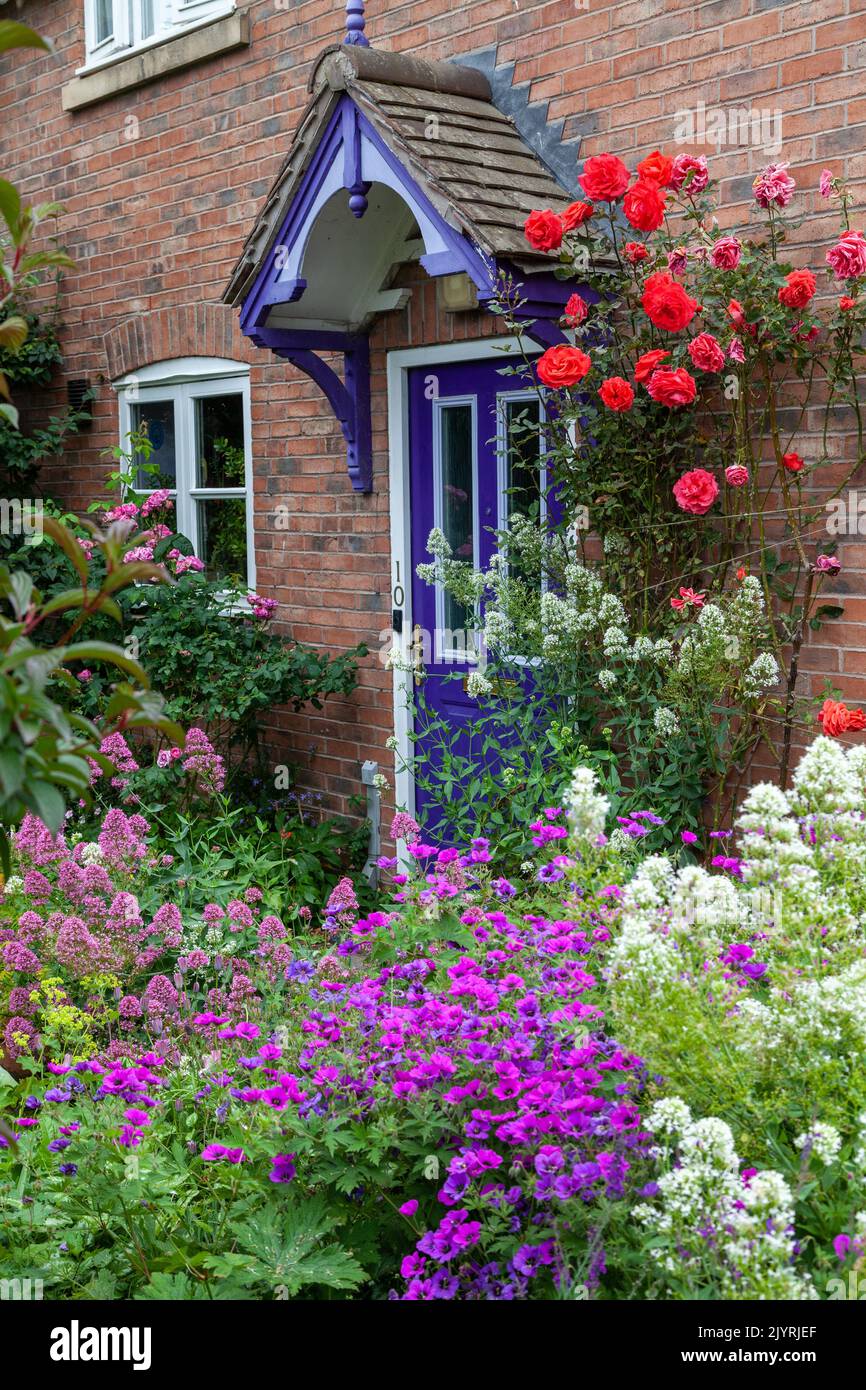 A beautiful cottage garden with roses climbing up the wall in Bishops ...