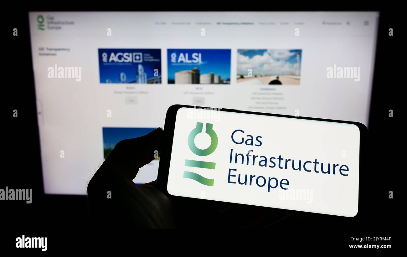 Person holding mobile phone with logo of association Gas Infrastructure ...