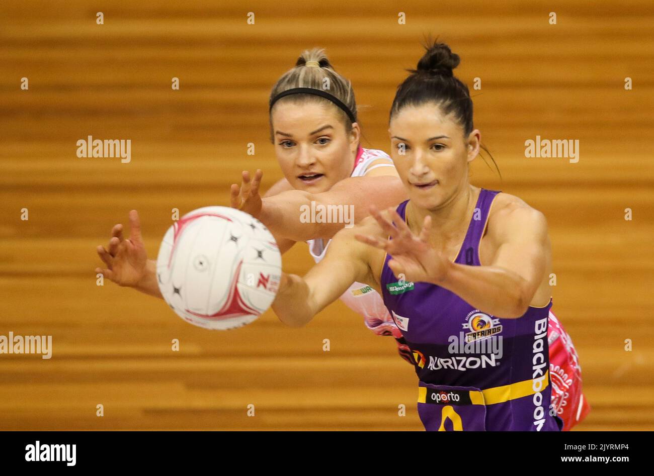 Kim Ravaillion of the Firebirds passes under pressure from Maisie ...