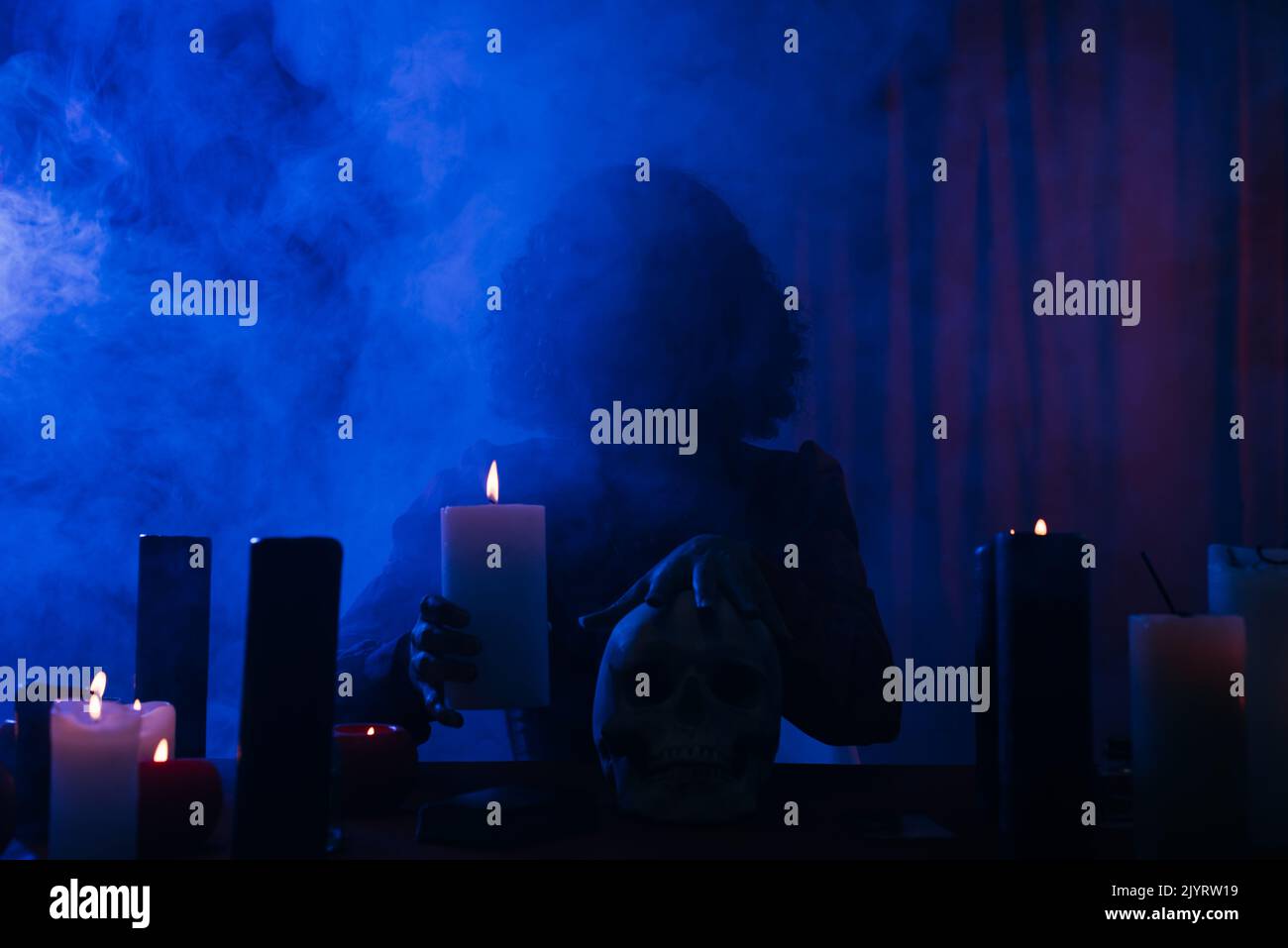 medium holding candle and touching skull during spiritual session in ...
