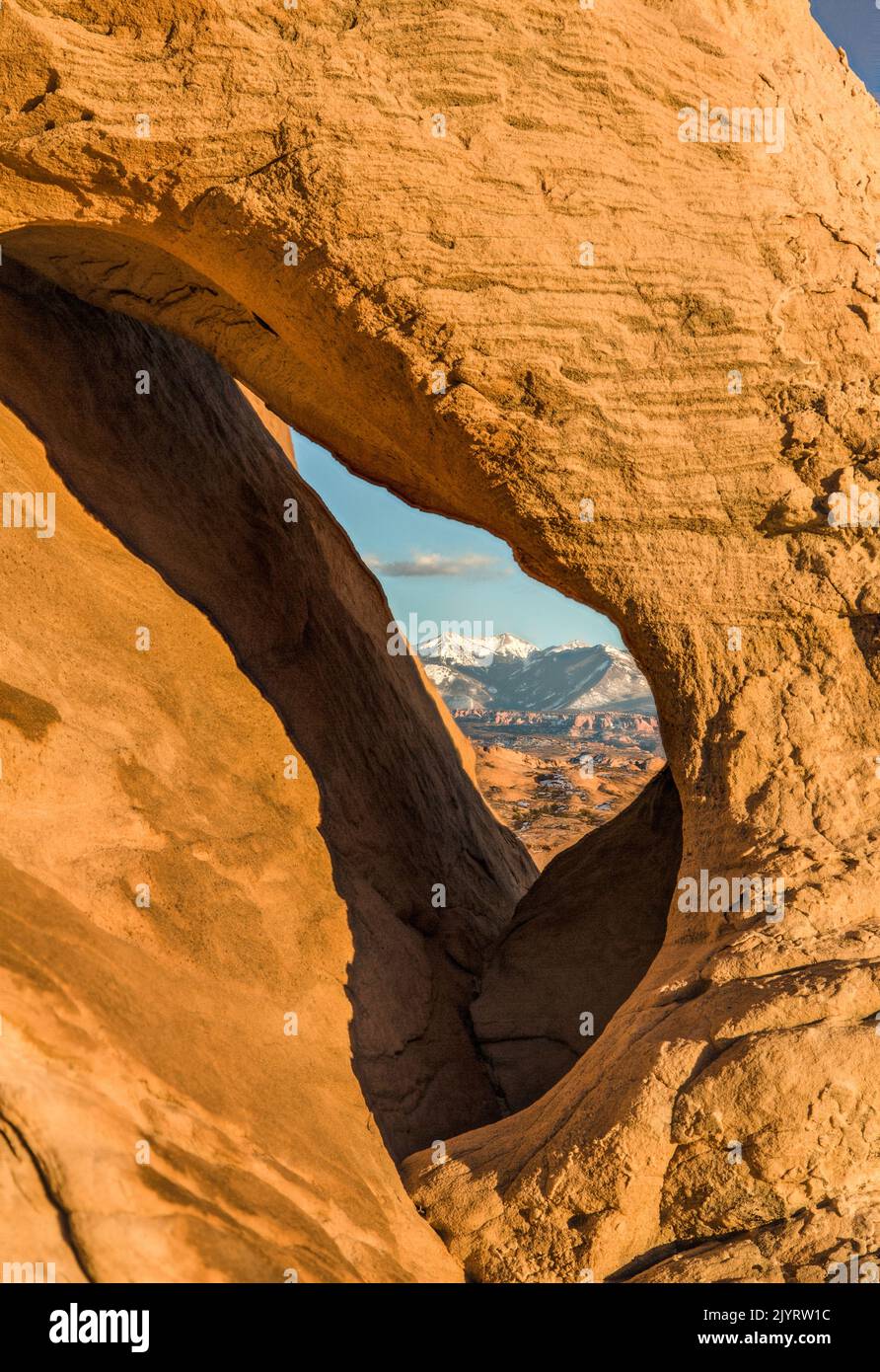 A small sandstone mini arch in Arches National Park frames the La Sal ...