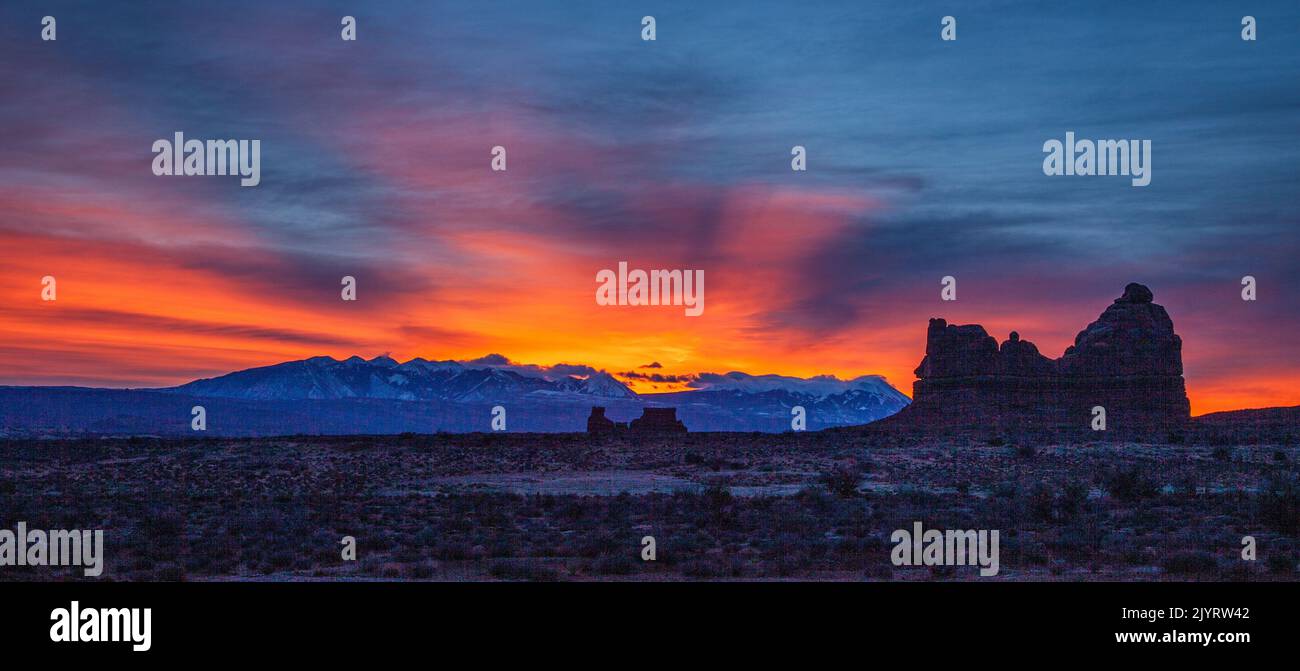 Colorful sunrise over the La Sal Mountains and a sandstone monolith as ...