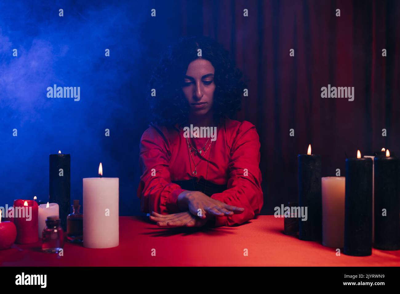 fortune teller sitting during magic session near burning candles on ...