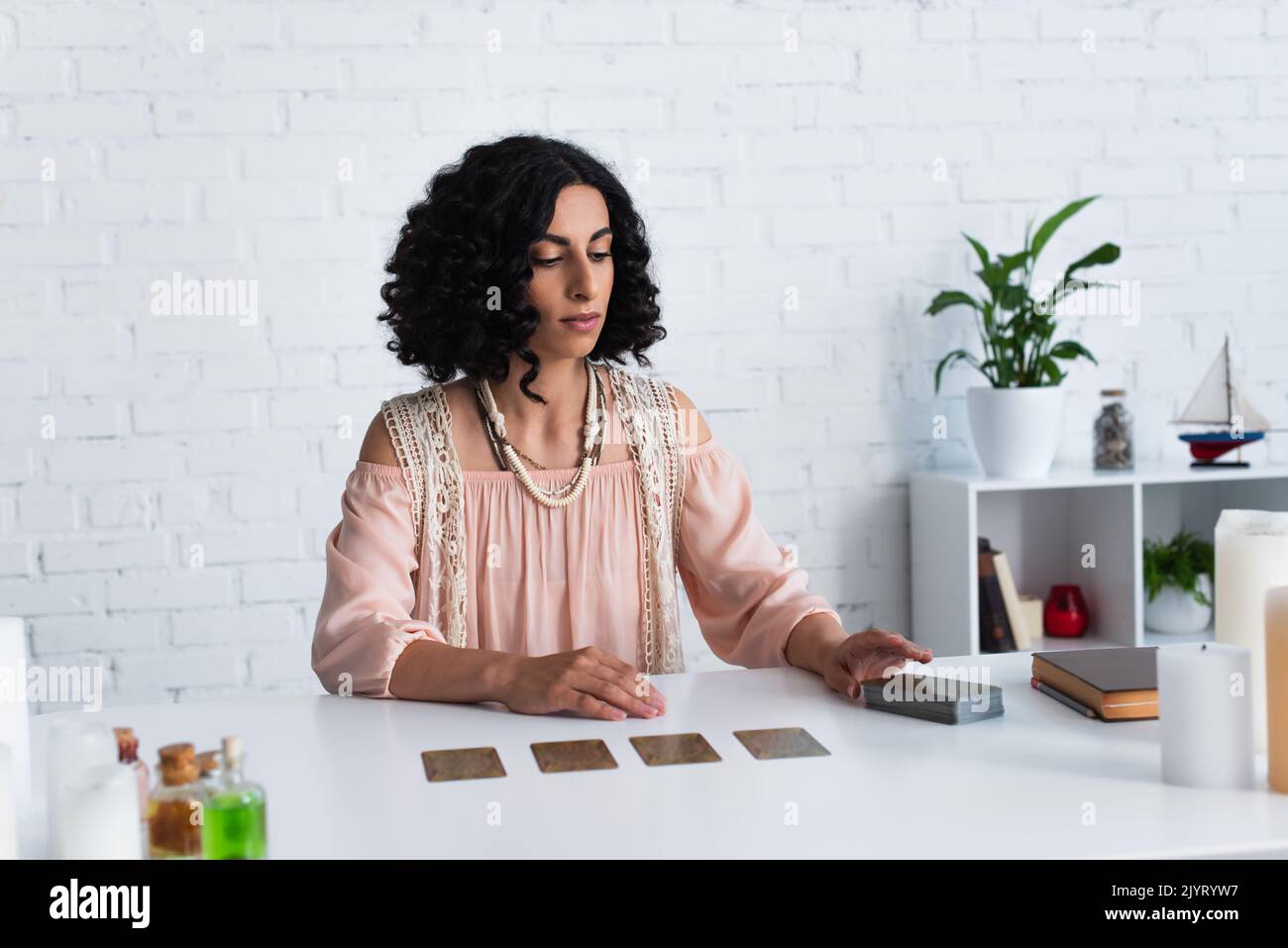 young fortune teller sitting near deck of tarot cards and prediction ...