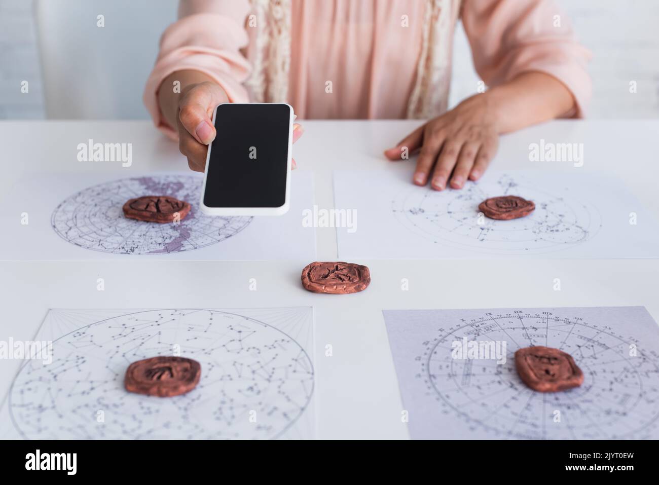 cropped view of oracle holding mobile phone with blank screen near ...