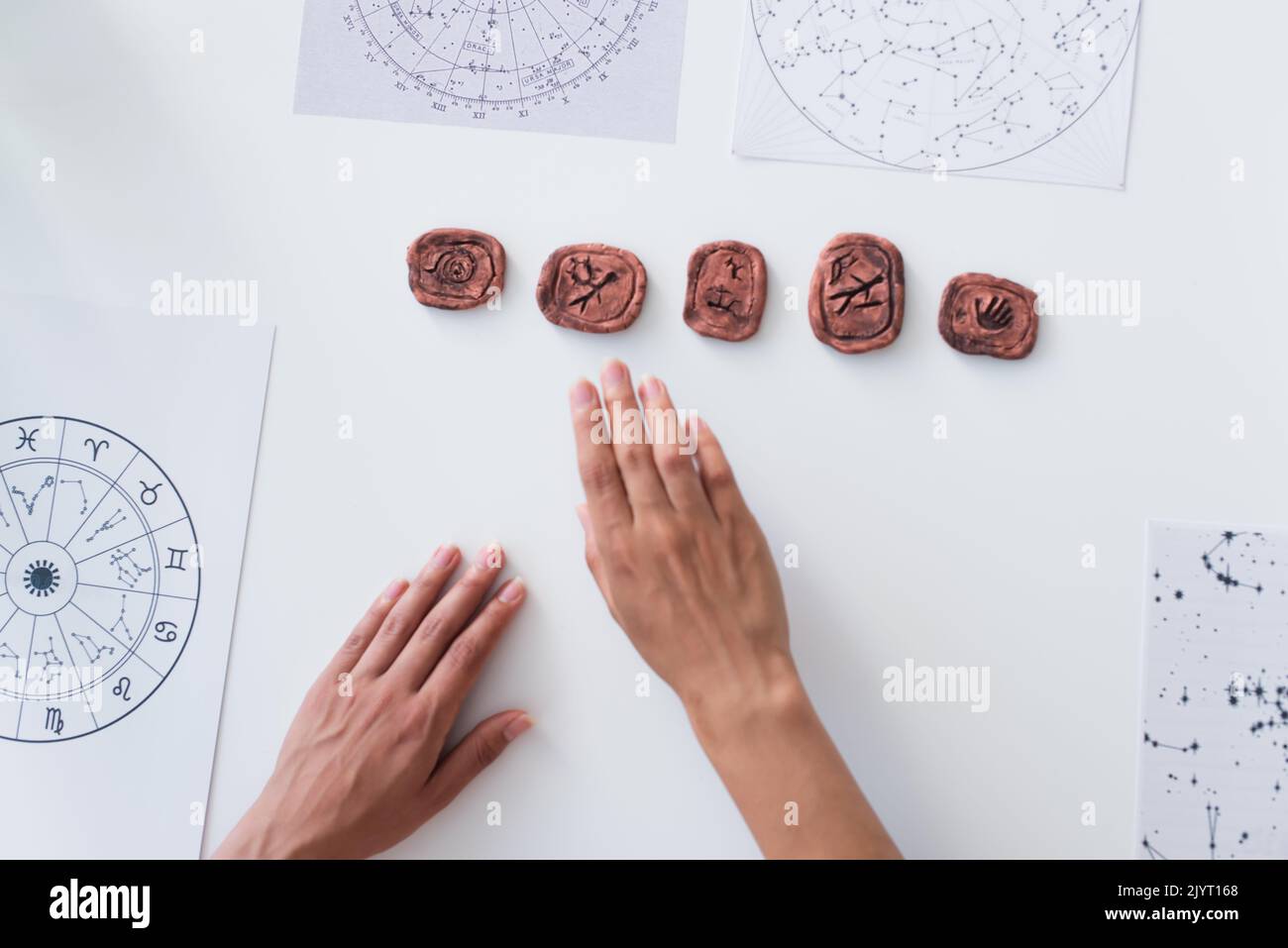 top view of cropped oracle near clay runes and star charts on table ...