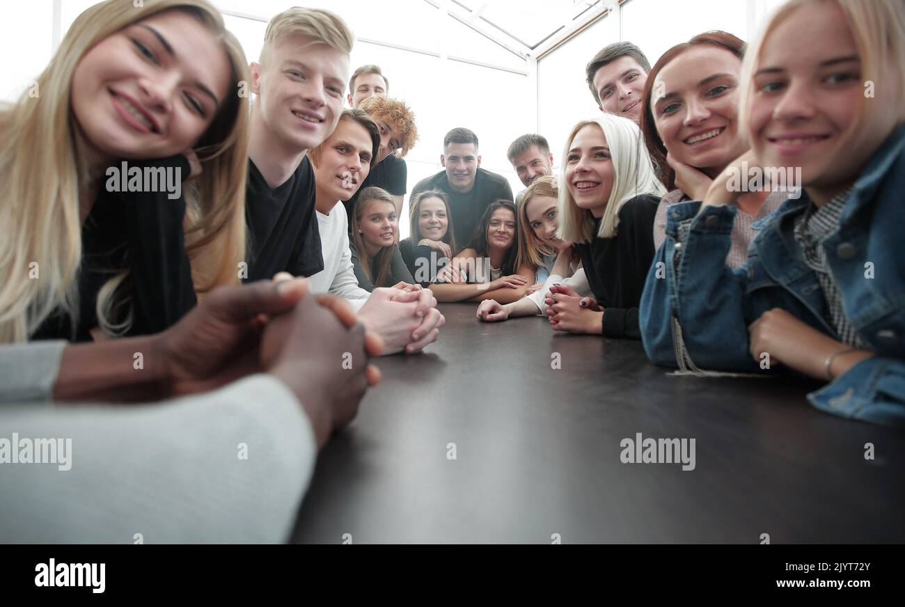 close up. a large group of friends sitting at a long table Stock Photo ...