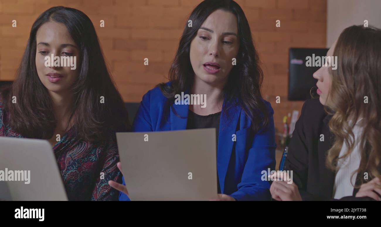 Women discussing work in front of laptop computer at corporate ...