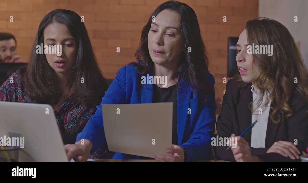 Women discussing work in front of laptop computer at corporate ...