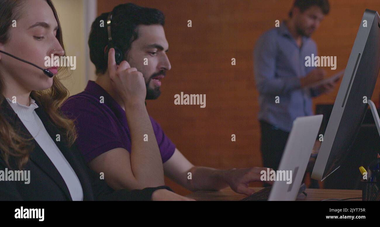 Telemarketers communicating with clients wearing headsets in front of ...