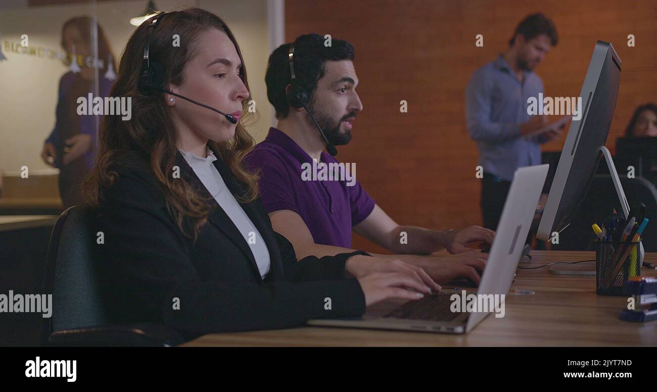 Telemarketers communicating with clients wearing headsets in front of ...