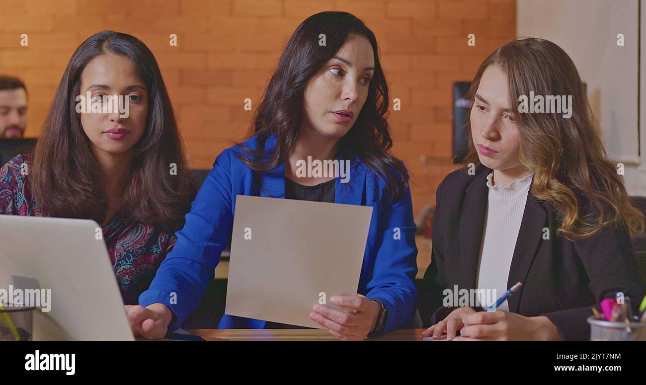 Women discussing work in front of laptop computer at corporate ...